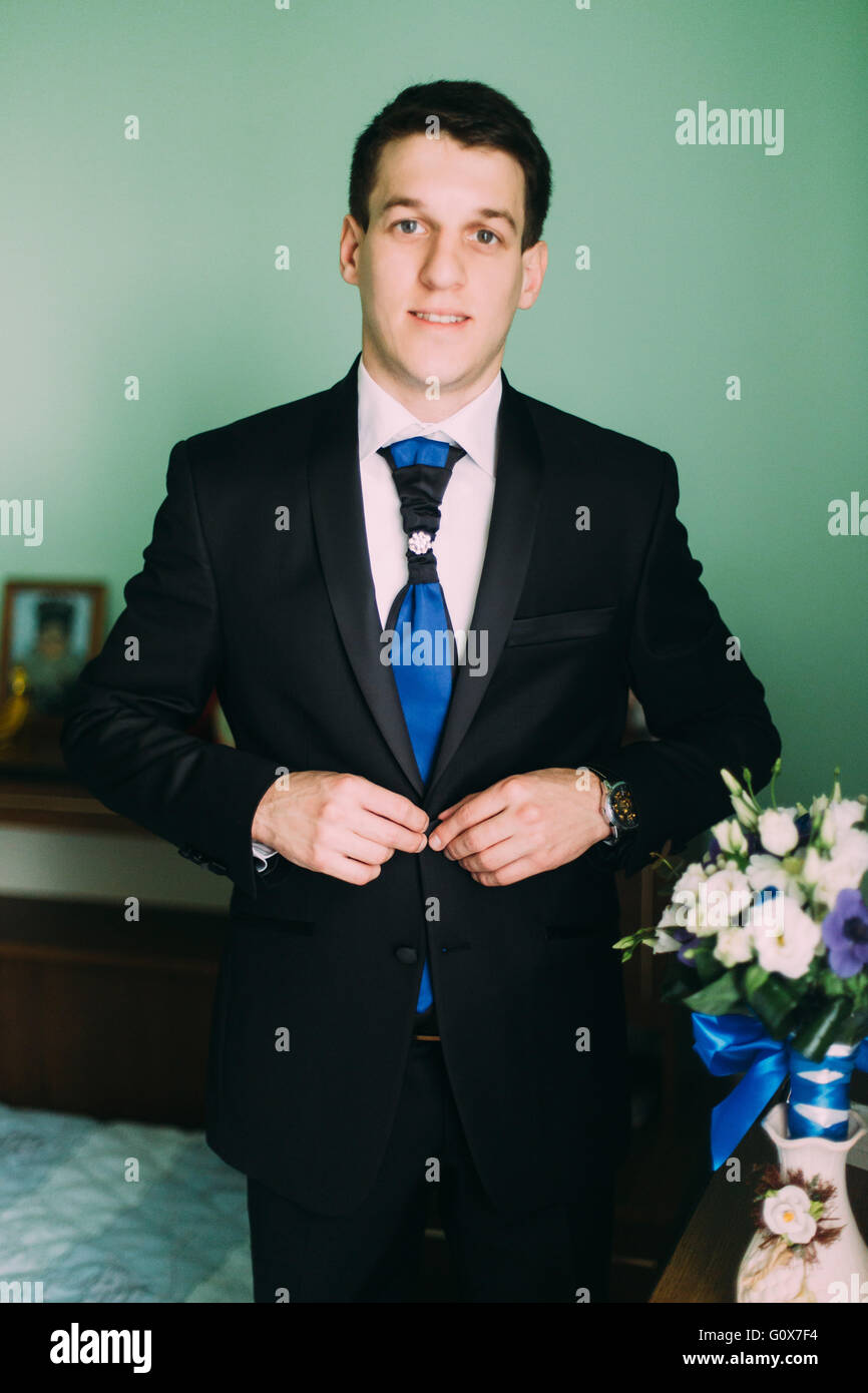 The elegant groom buttons jacket standing near window Stock Photo - Alamy