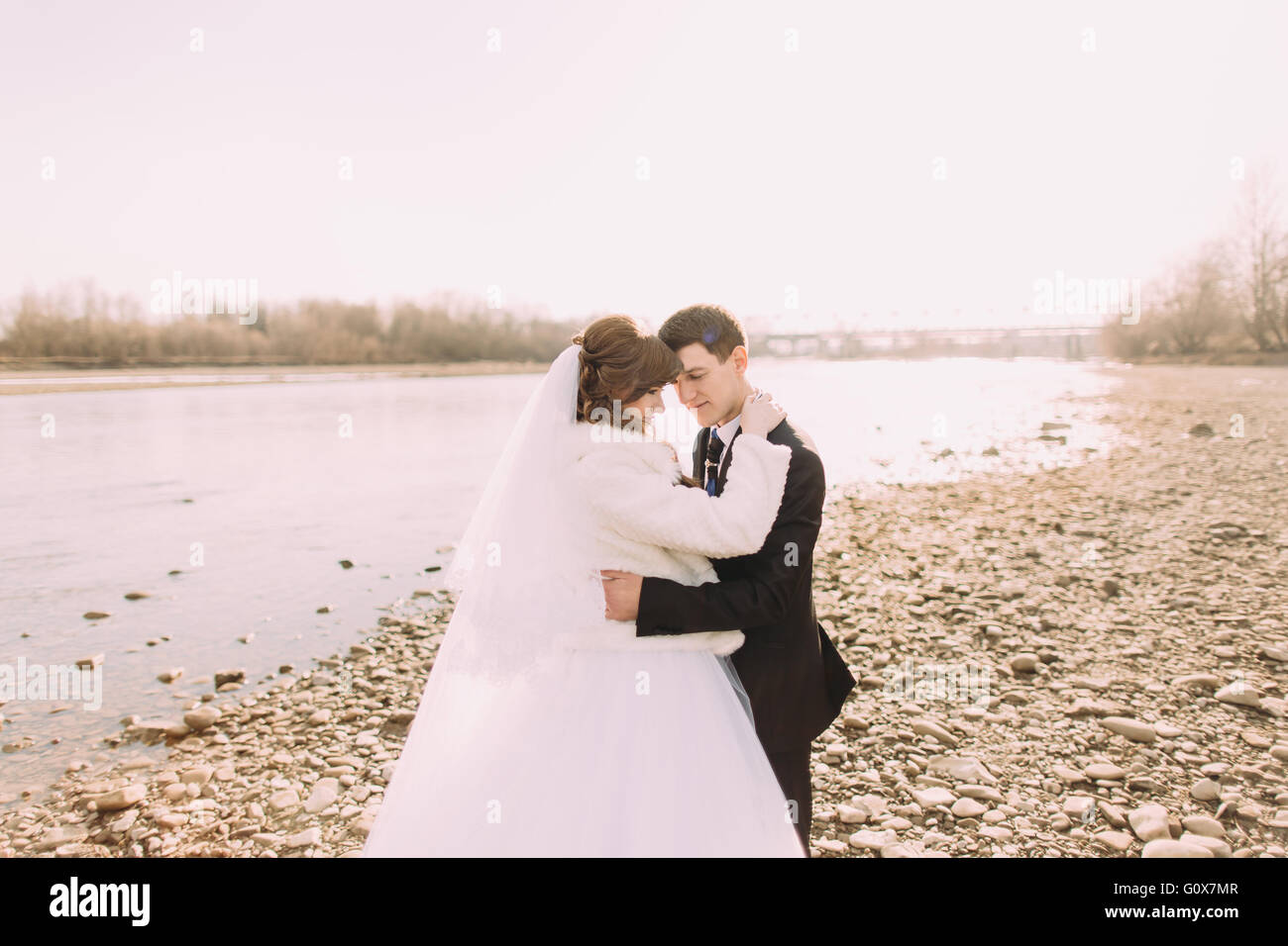 Happy wedding couple, bride and groom embracing face-to-face neat river ...
