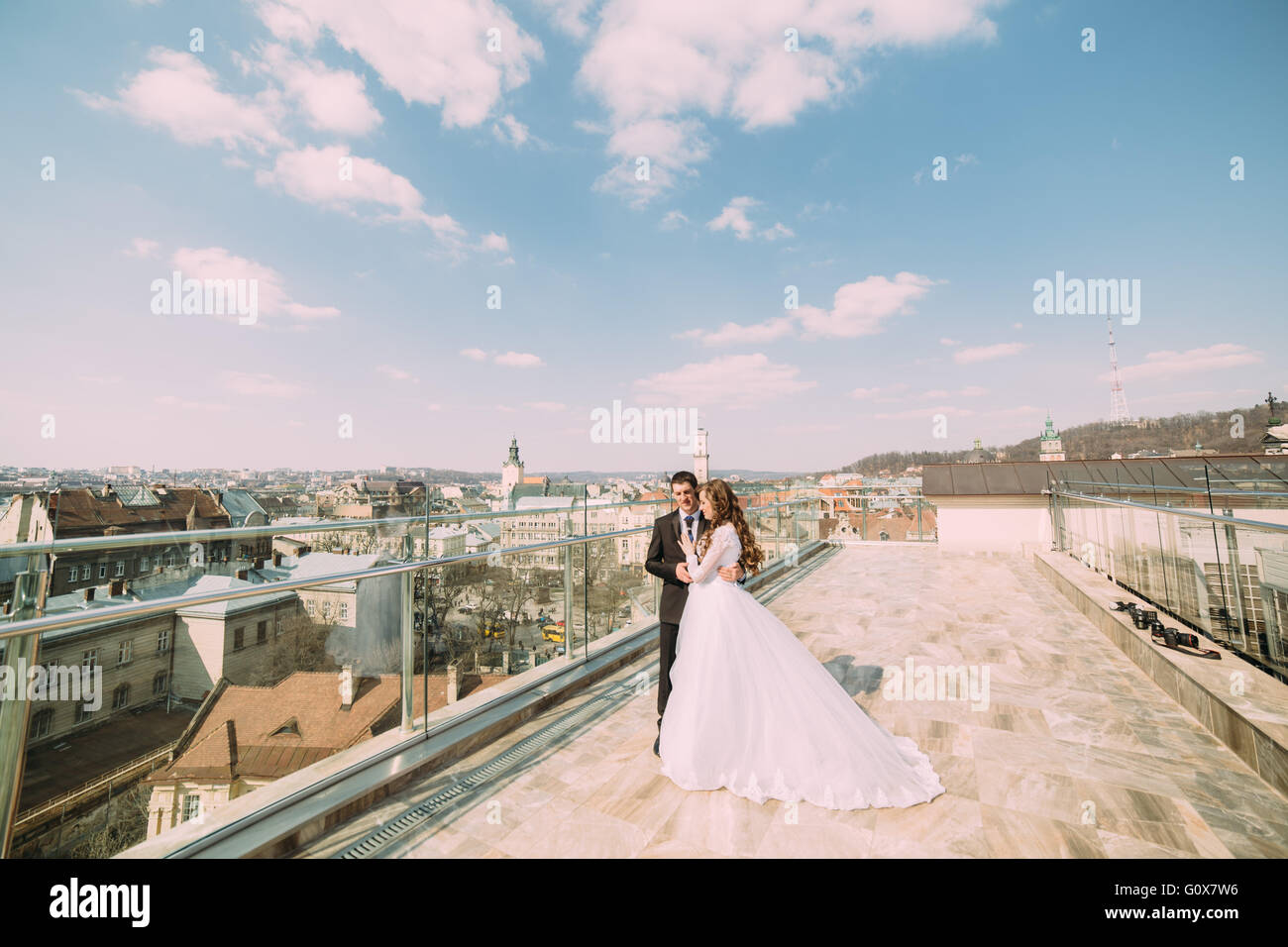 Beautiful groom and bride embracing on roof top building with city ...