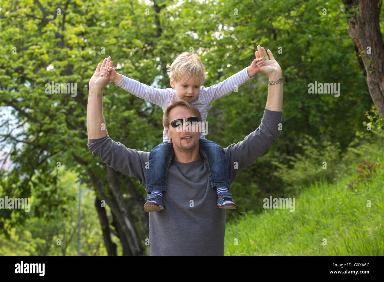 Blond boy sitting on fathers shoulder outdoors Stock Photo - Alamy