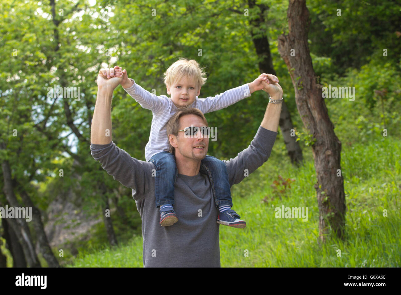 Blond boy sitting on fathers shoulder outdoors Stock Photo - Alamy