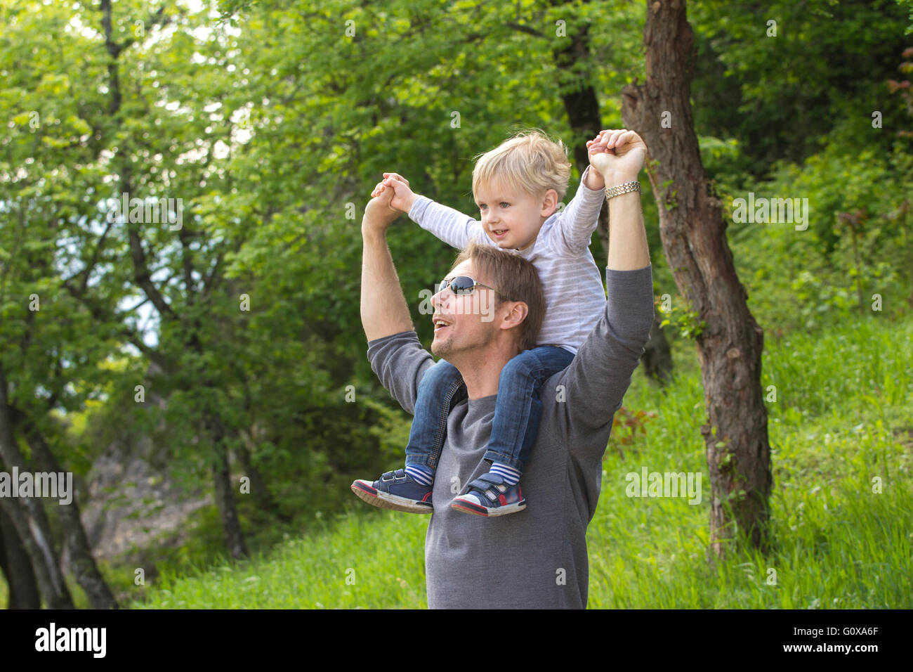 Blond boy sitting on fathers shoulder outdoors Stock Photo - Alamy