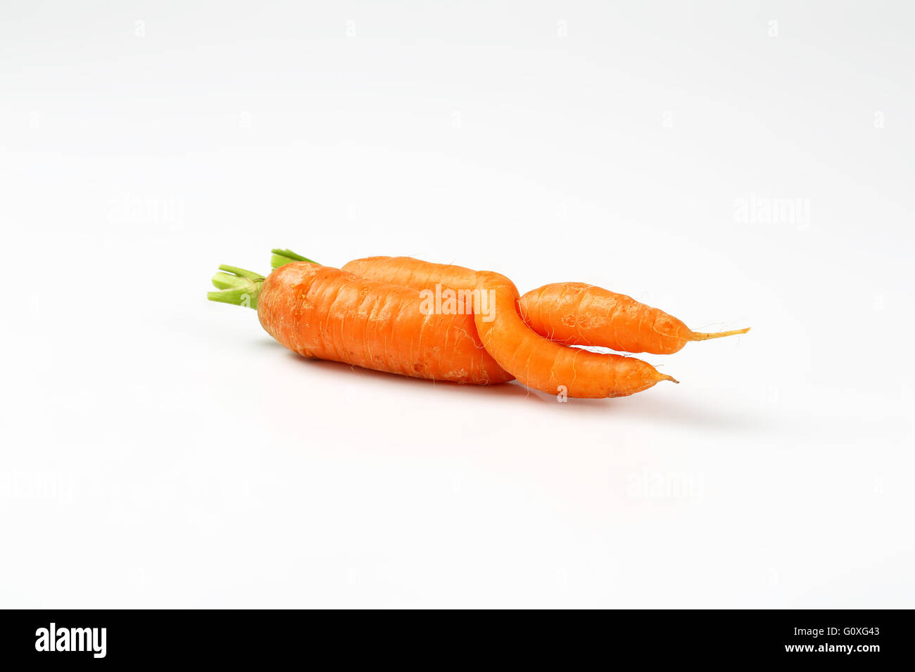 two twisted carrots on white background Stock Photo - Alamy