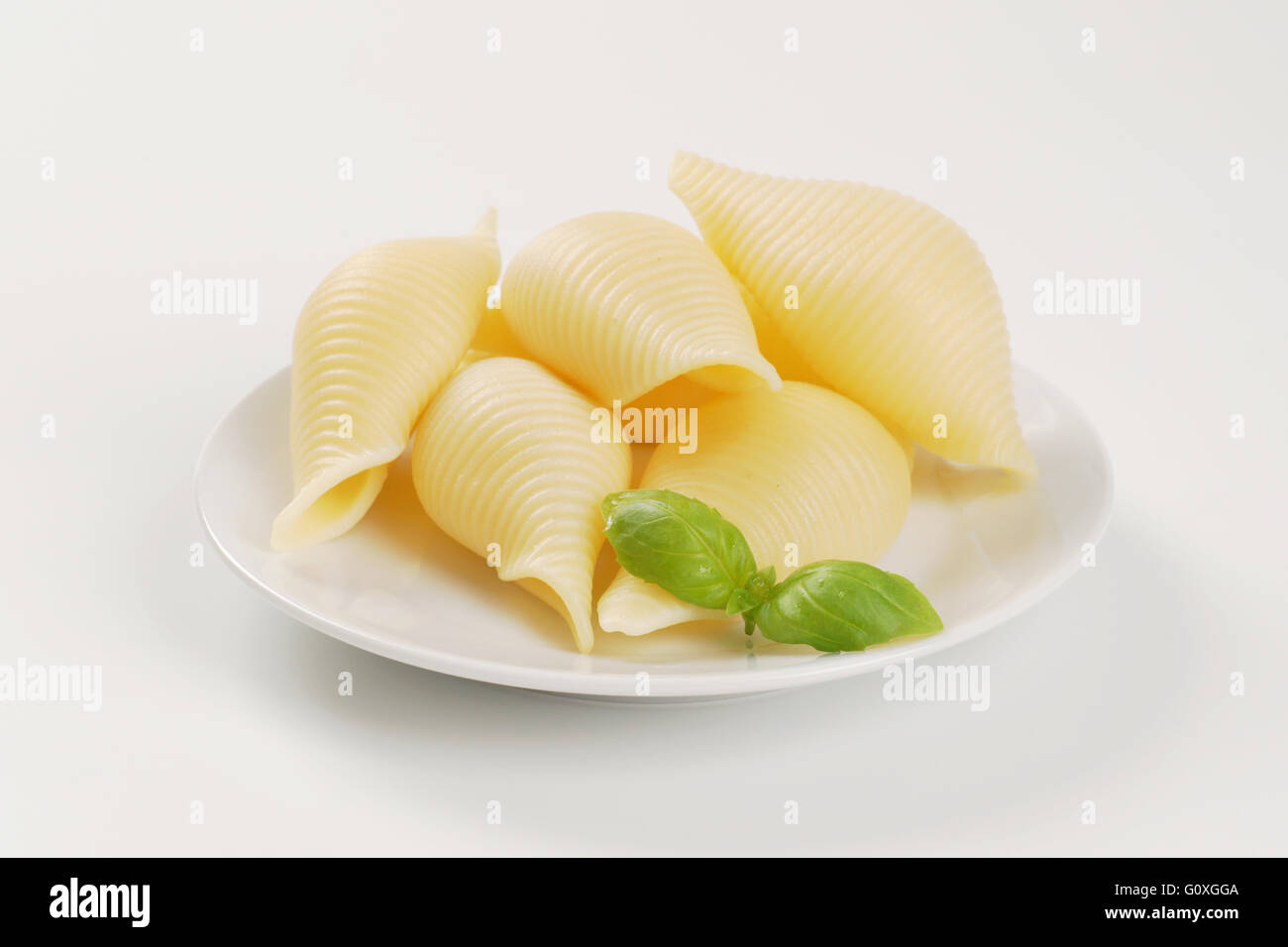 plate of cooked pasta shells on white background Stock Photo - Alamy