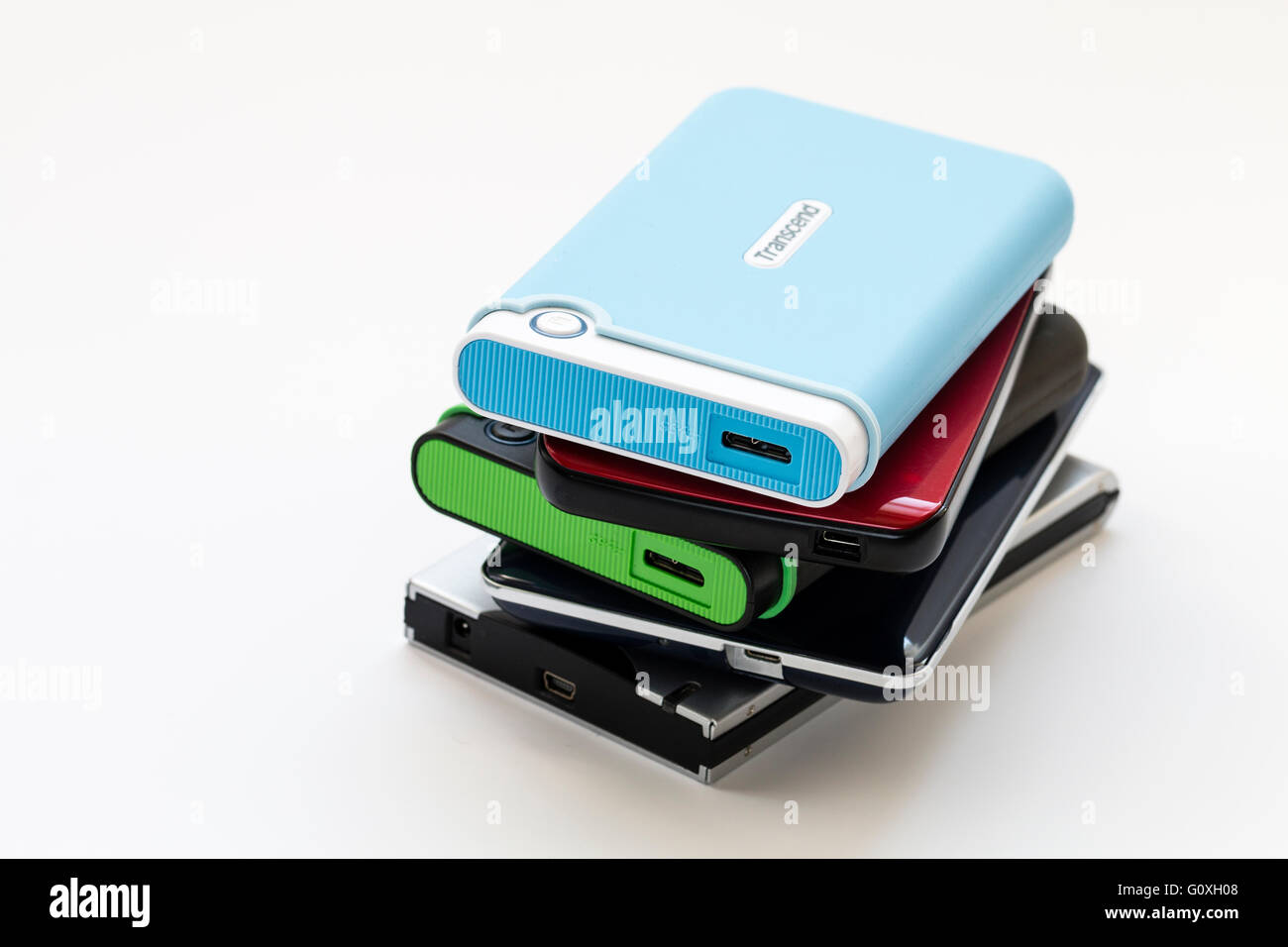 Stack of five different kinds and colours of portable hard drives. Top ...