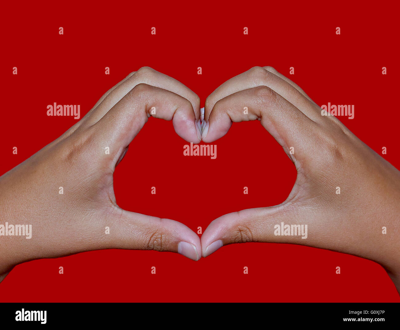 A child's hands forming a heart shape on a red background Stock Photo ...