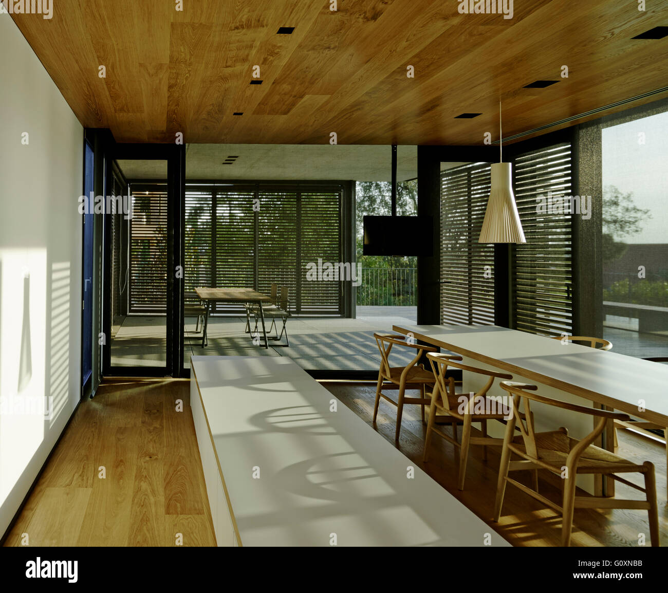 Spacious dining area with long white table and chairs. White bench and ...