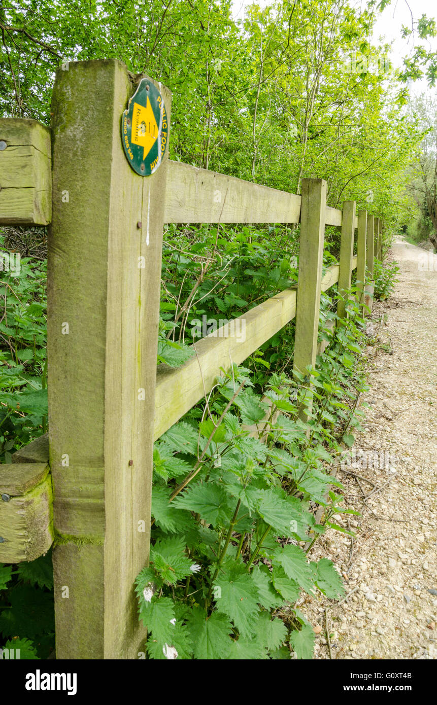 A wooden fence along the side of a public footpath. A trail marker ...