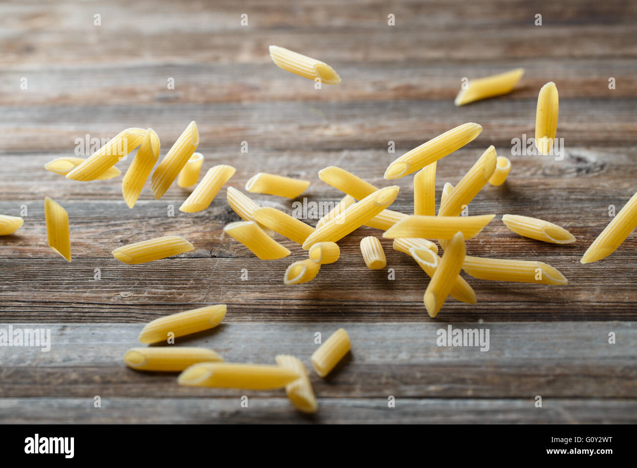 Falling penne pasta. Flying yellow raw macaroni over black background ...