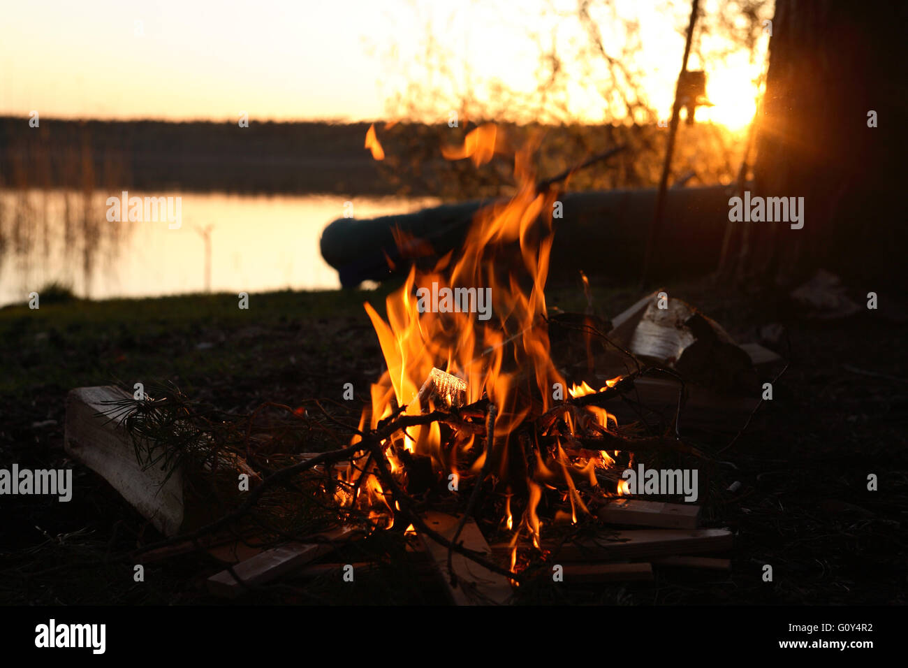 Camp-fire on river bank an sunset Stock Photo - Alamy