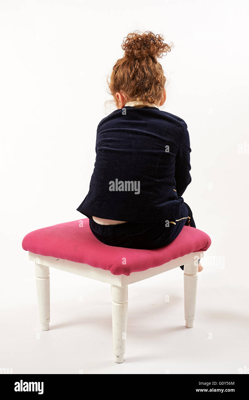 Little girl in black suit sitting back Stock Photo - Alamy