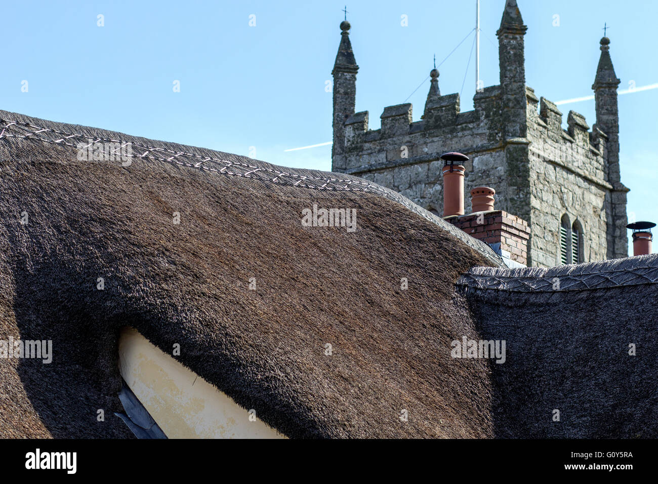Cob and thatch cottage with church of village of Drewesteignton ...