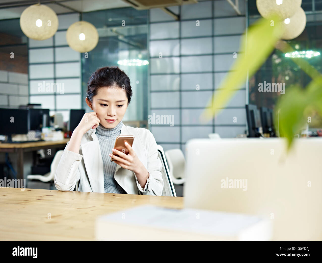 young asian office worker using cellphone in office Stock Photo - Alamy