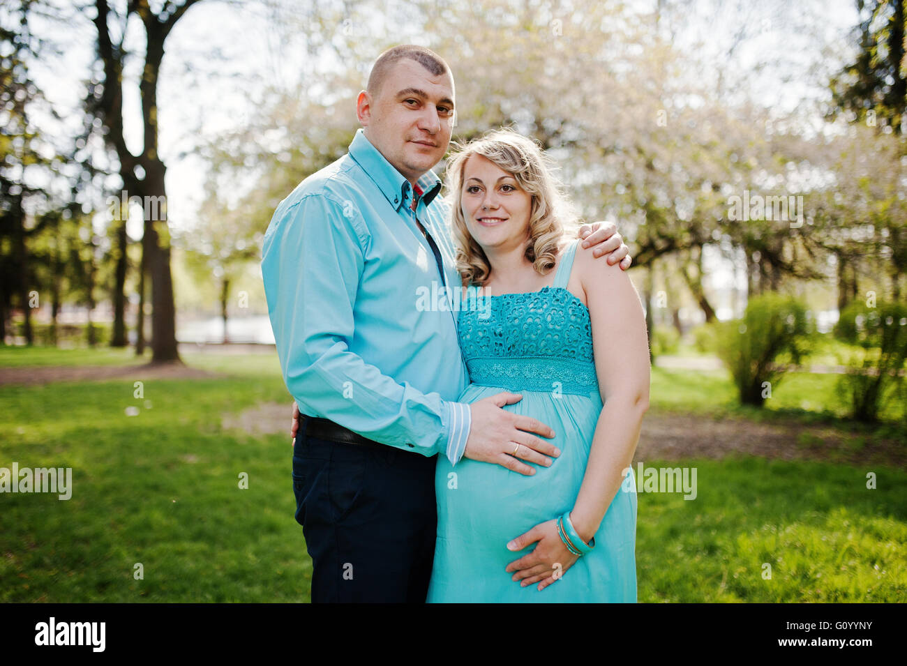 Happy pregnant couple hugging in nature background spring blossom tree ...