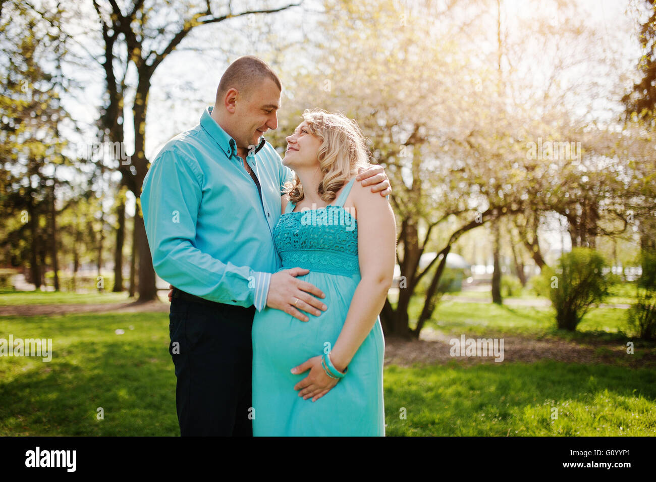 Happy pregnant couple hugging in nature background spring blossom tree ...