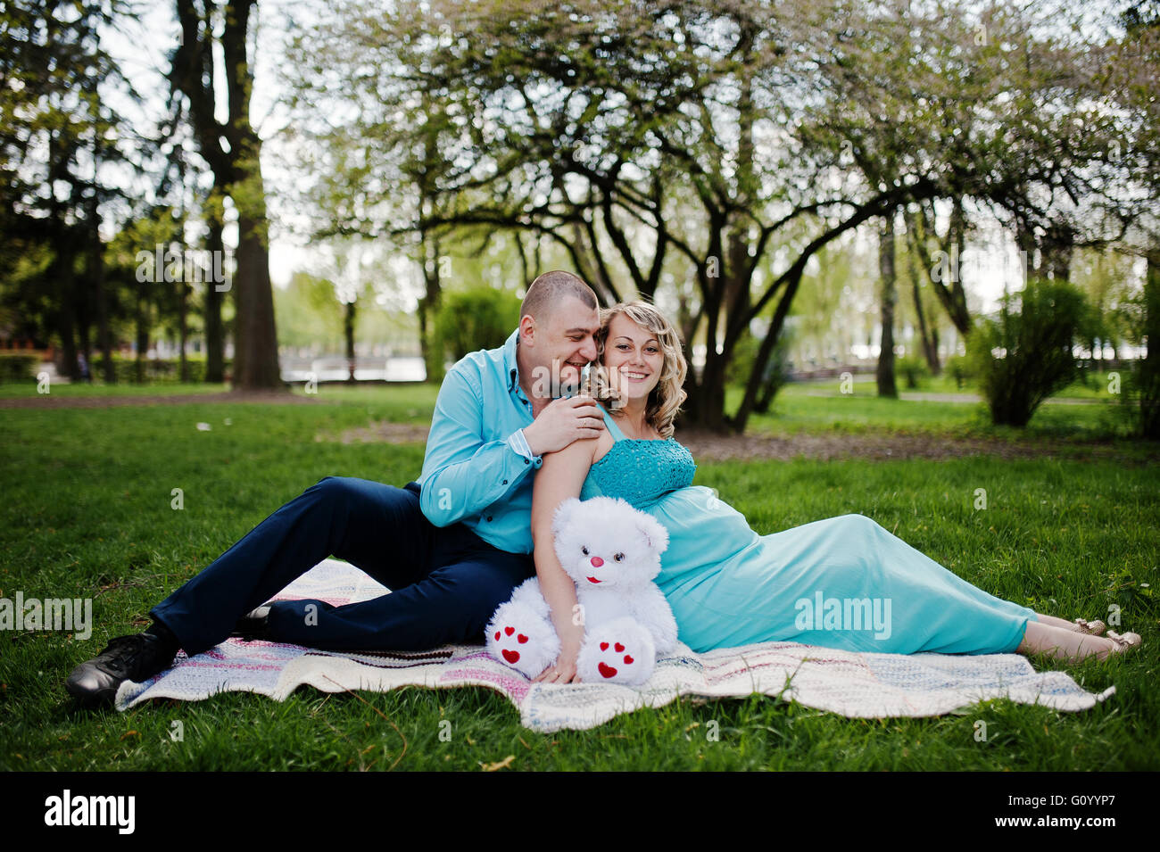 Happy pregnant couple hugging and sitting on plaid background spring ...