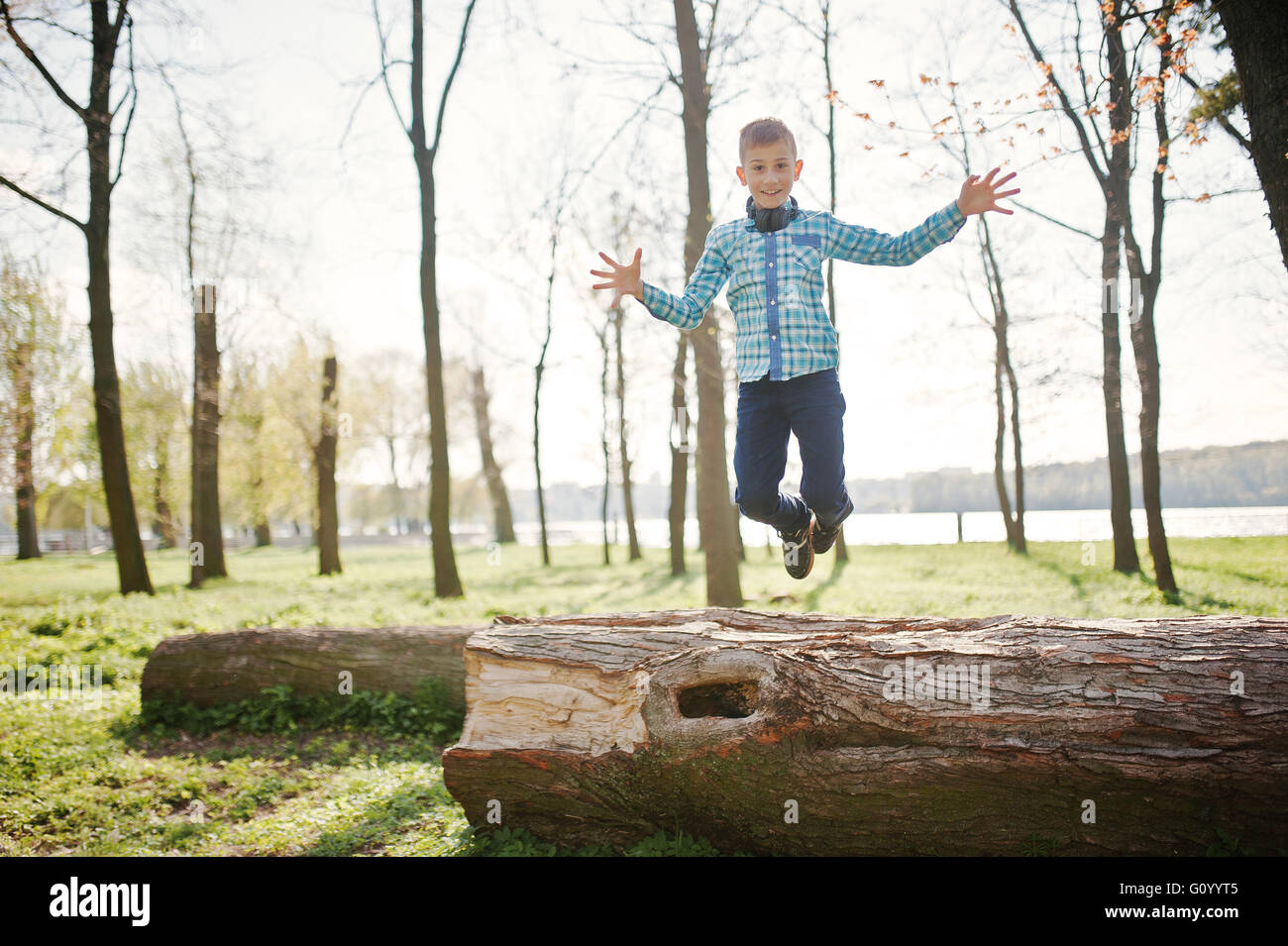 Little fun boy jump froom tree stump at park Stock Photo - Alamy