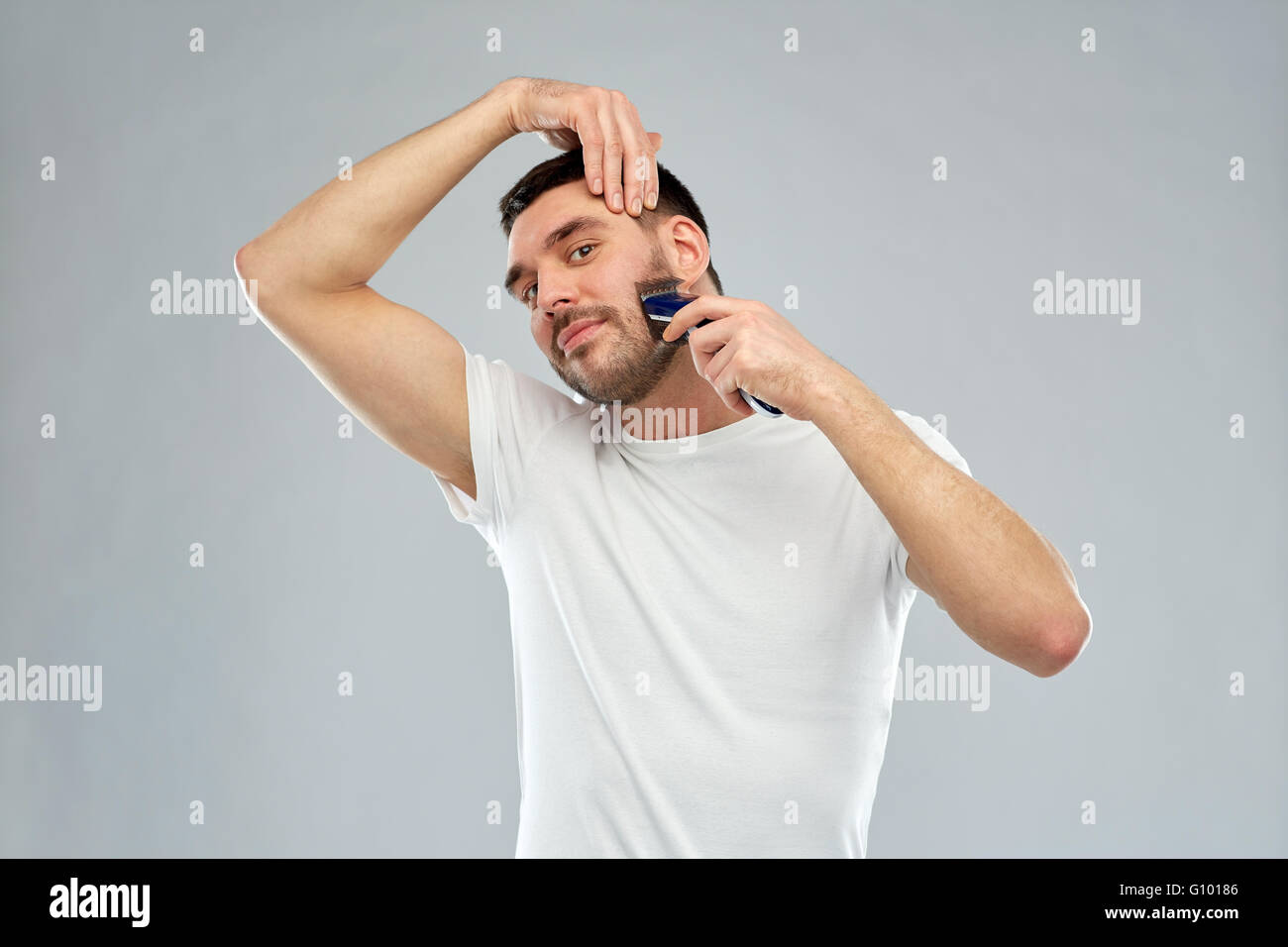 smiling man shaving beard with trimmer over gray Stock Photo - Alamy