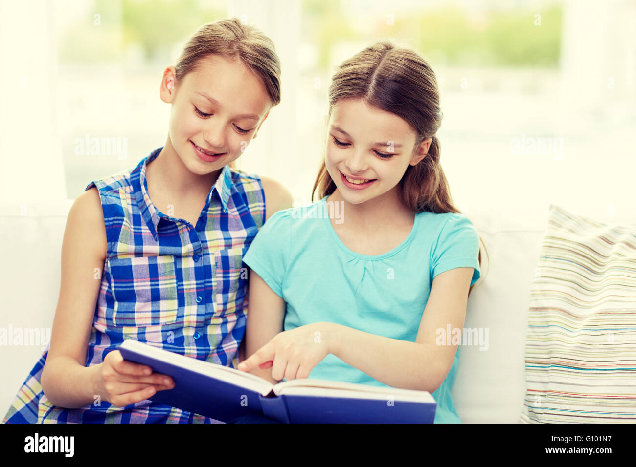 two happy girls reading book at home Stock Photo - Alamy