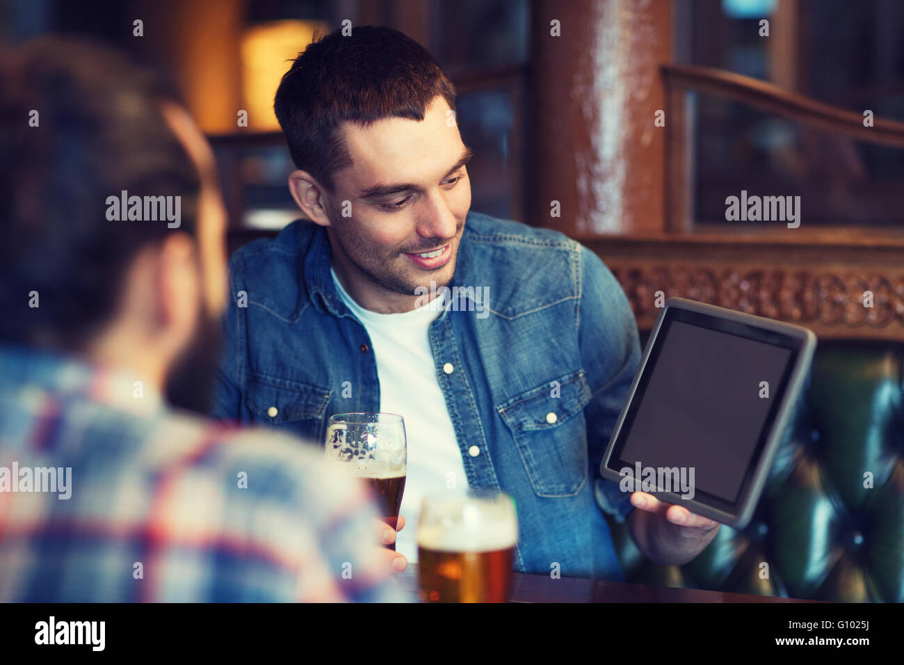 male friends with tablet pc drinking beer at bar Stock Photo - Alamy