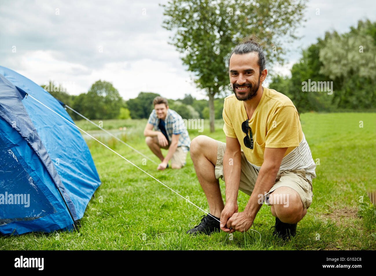 smiling friends setting up tent outdoors Stock Photo - Alamy