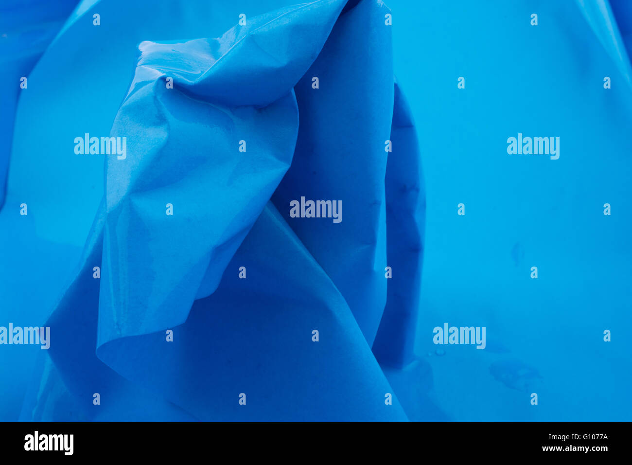 Crumpled paper put in water in blue background Stock Photo - Alamy