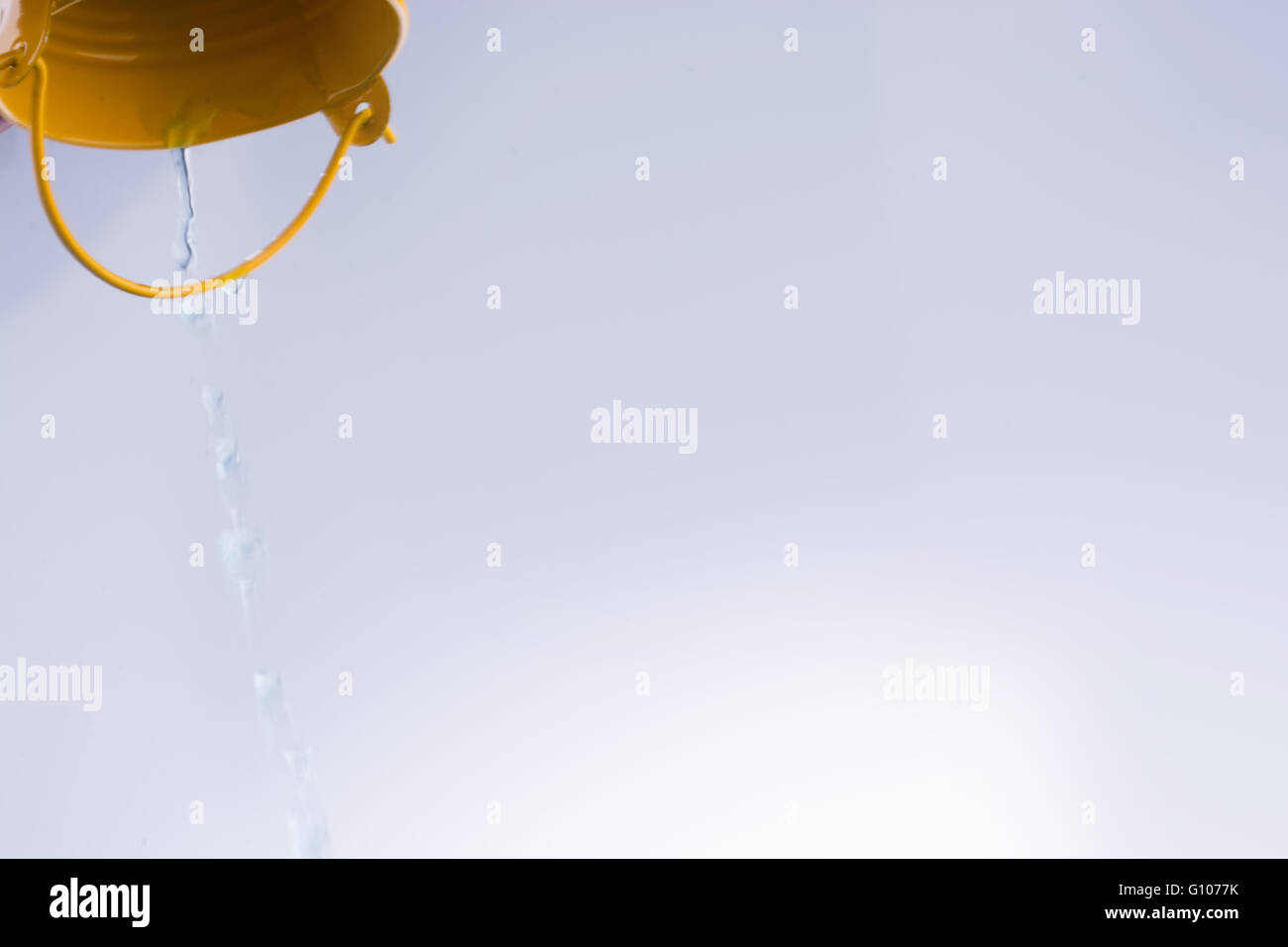 Water flowing out of little yellow bucket Stock Photo - Alamy