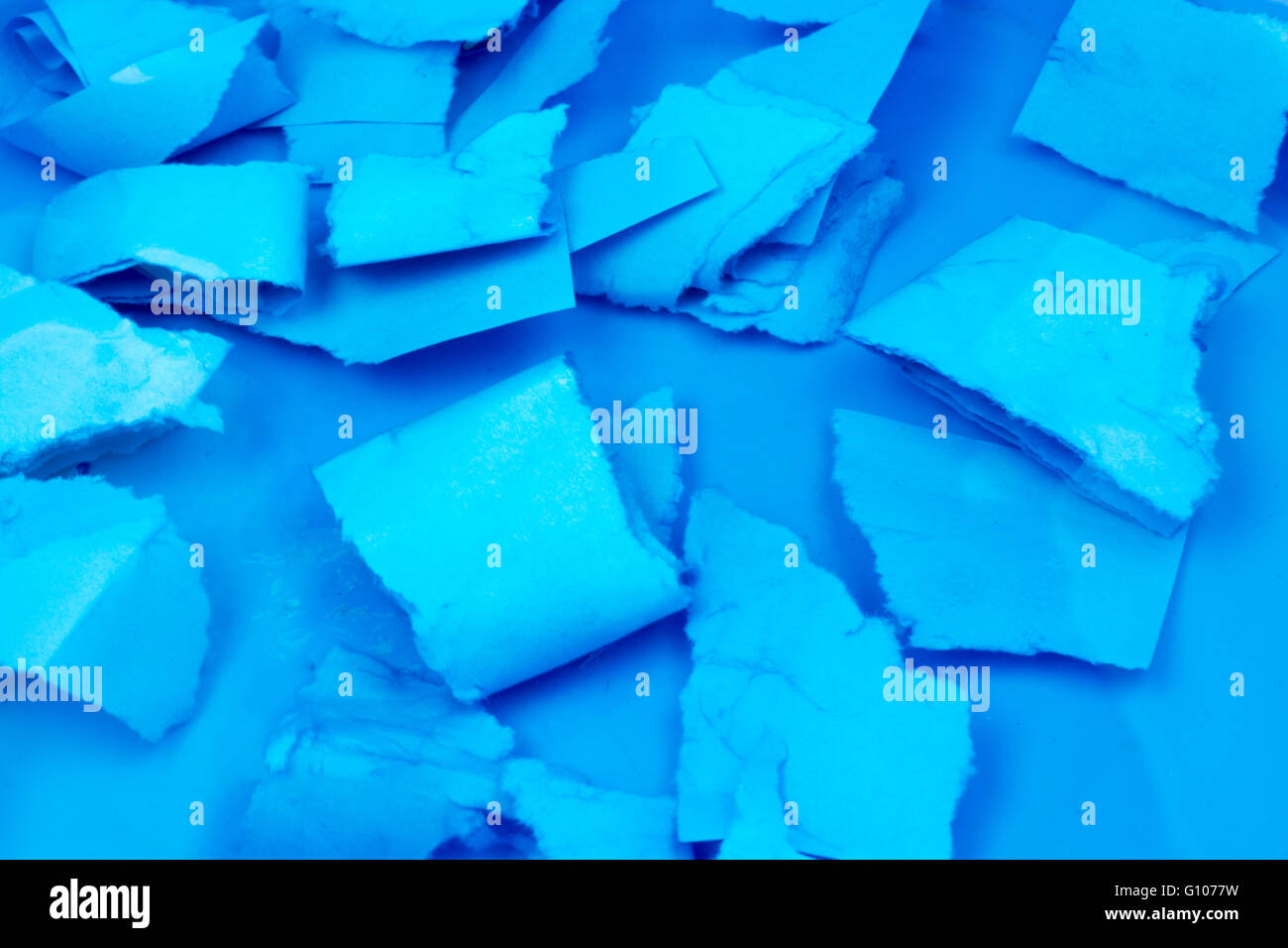 Turn paper pieces in water in blue background Stock Photo - Alamy