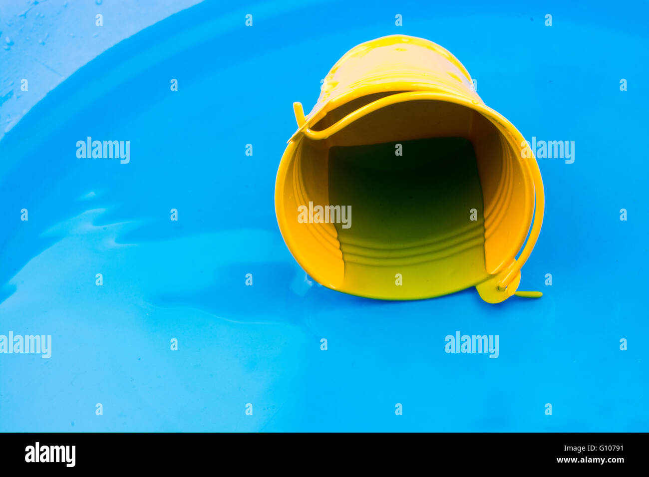 little yellow bucket in water in blue background Stock Photo - Alamy