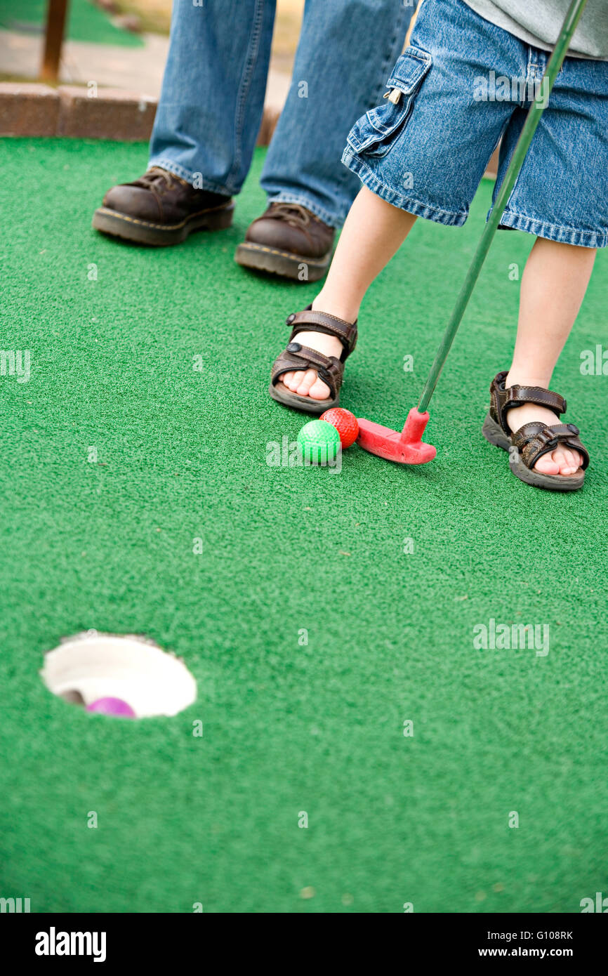 Cute, typical family playing outdoor mini-golf Stock Photo - Alamy