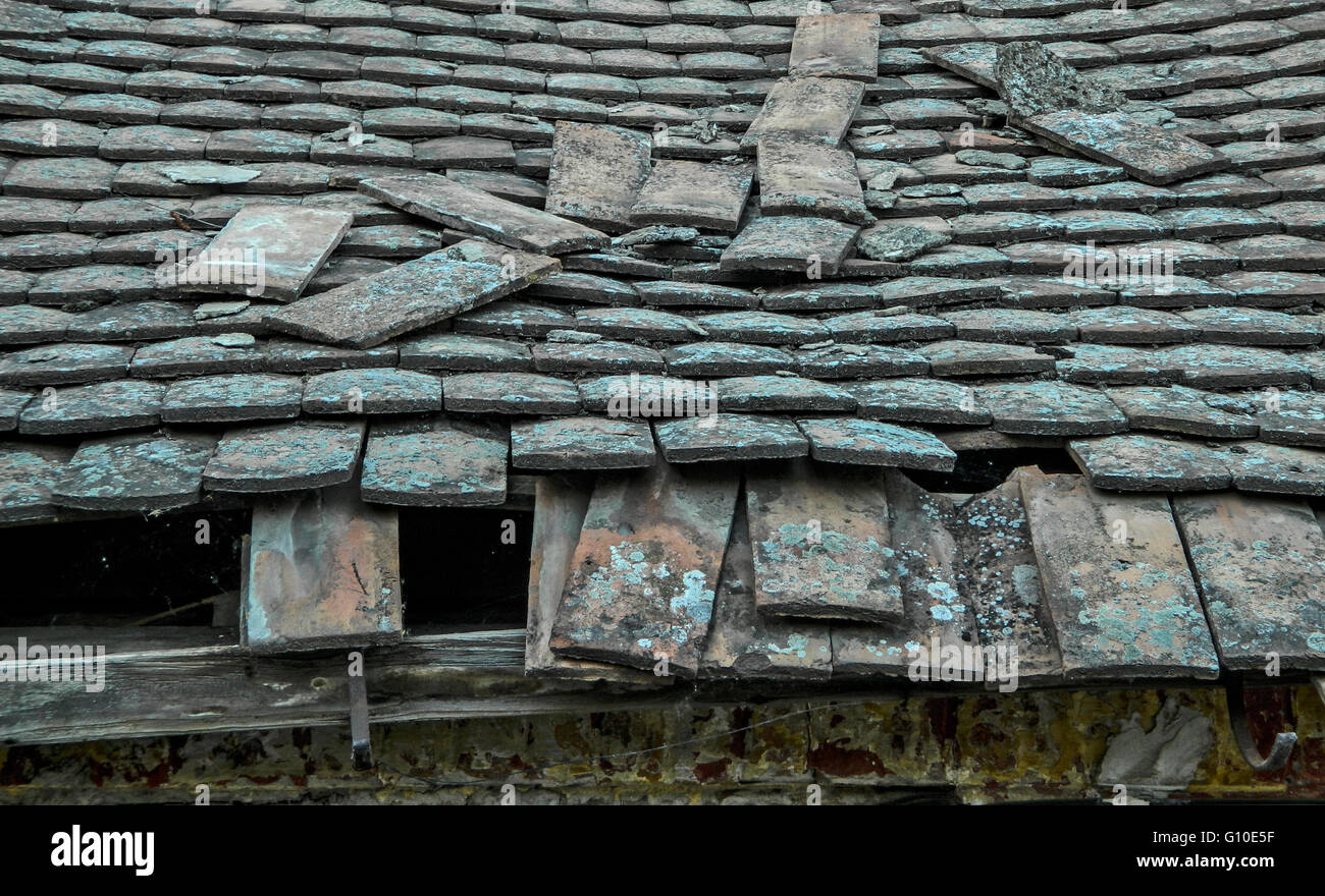 A decrepit old house with a damaged and devastated roof and tiles Stock ...