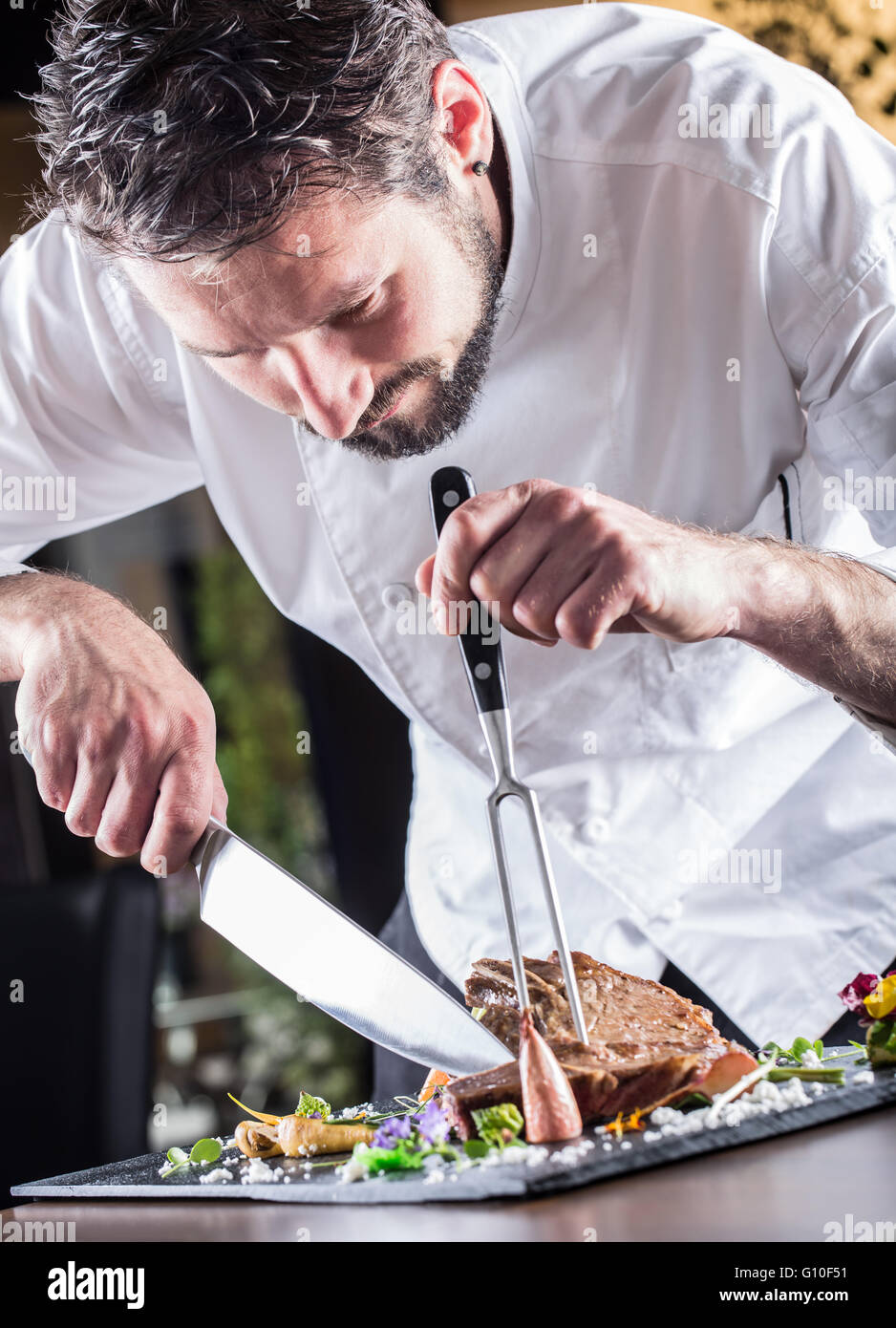 Chef in hotel or restaurant kitchen cooking, only hands. He is working ...