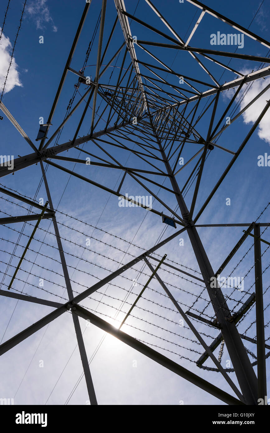 Looking up into the frame of an electricity pylon with clear blue sky ...