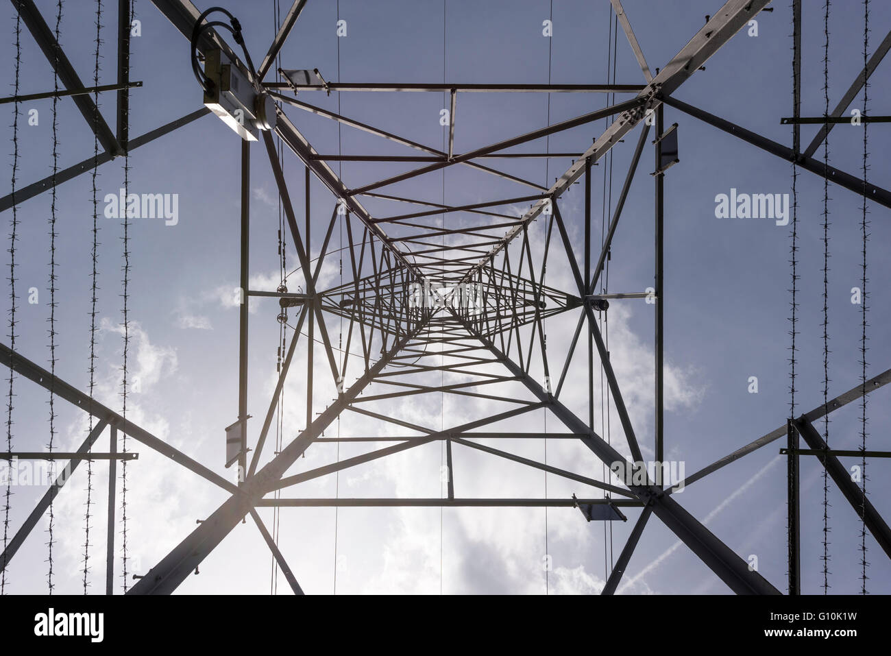 Looking up into the frame of an electricity pylon with clear blue sky ...