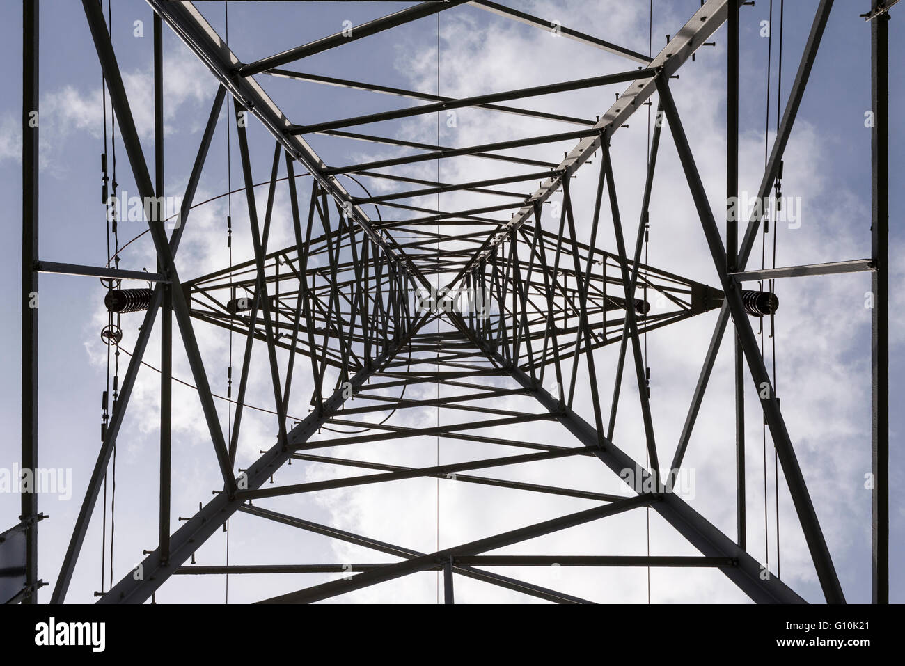 Looking up into the frame of an electricity pylon with clear blue sky ...