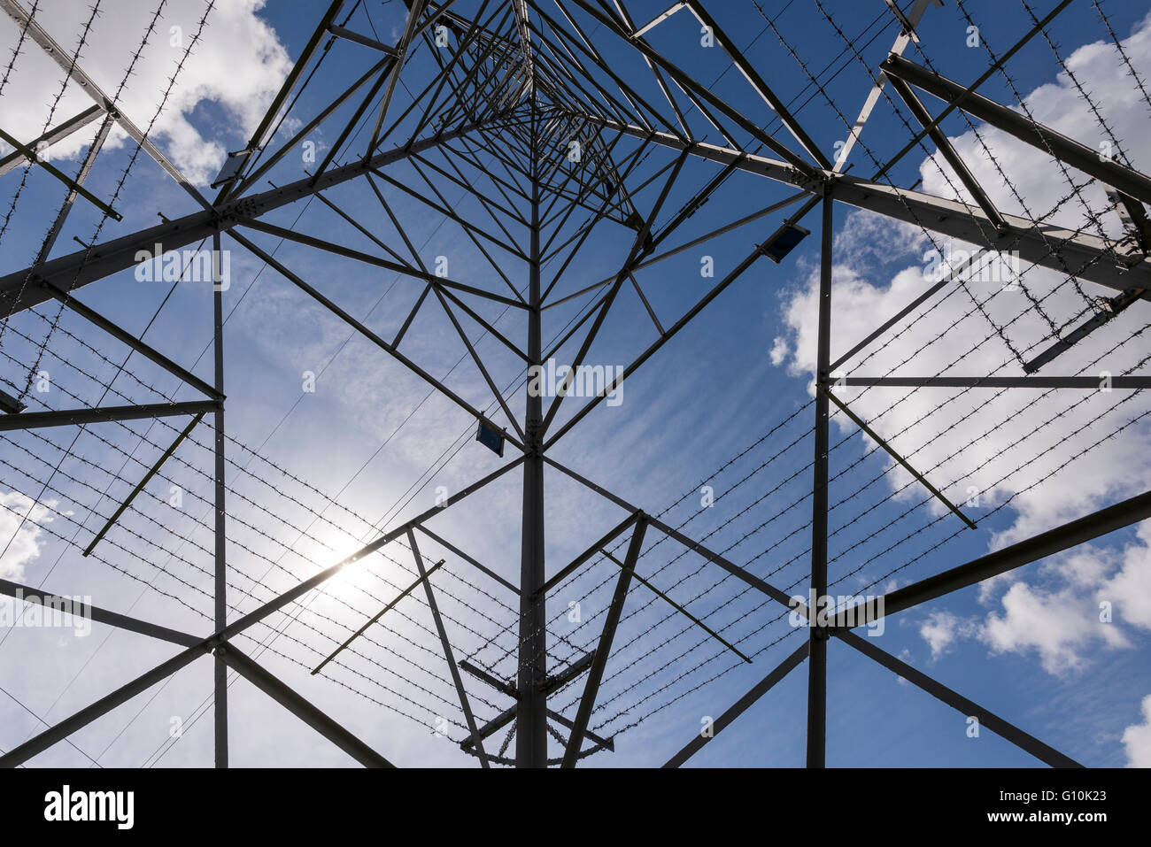 Looking up into the frame of an electricity pylon with clear blue sky ...