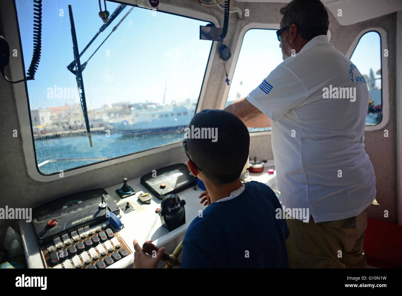 Young boy driving ferry boat from cruise ship to Mykonos, Greek Islands ...