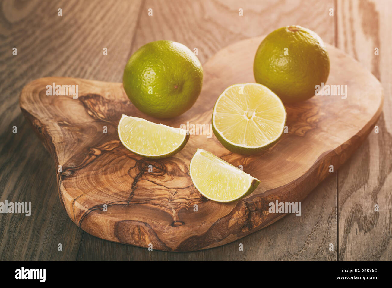ripe limes on olive board over oak table Stock Photo - Alamy