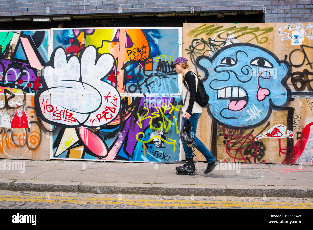 Boy on Rollerblades skating on the pavement in front of a wall with a ...