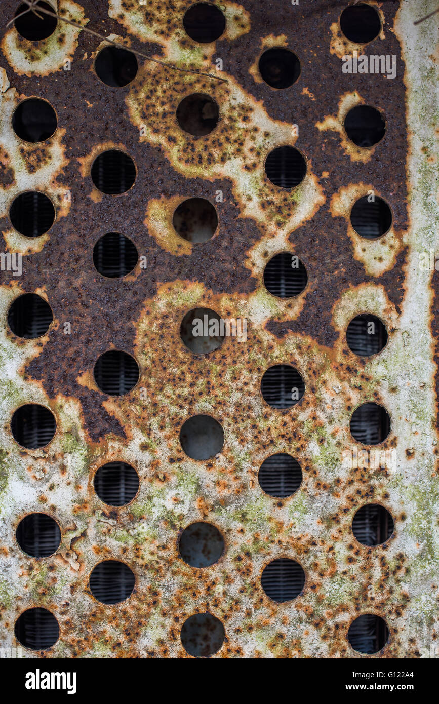 Circular holes in a air vent on a rusted abandoned mine train ...