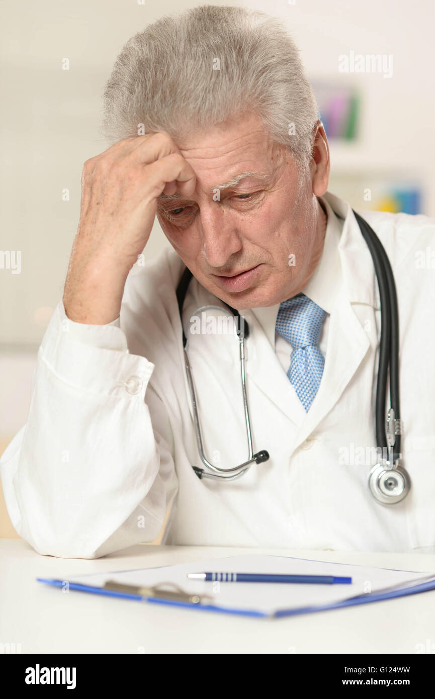 Elderly doctor at a table Stock Photo - Alamy