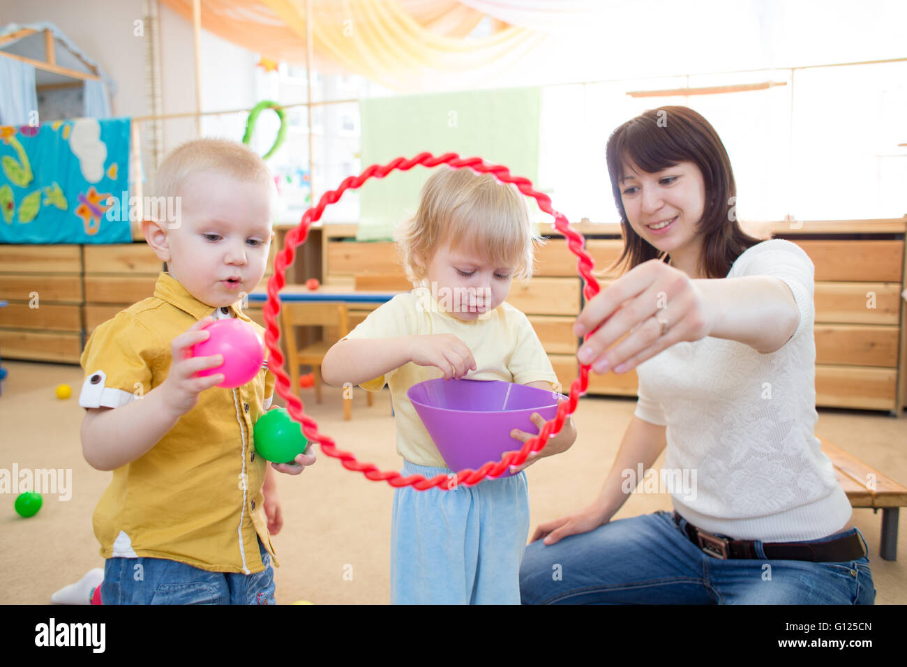 Happy children playing with ball and ring in kindergarten Stock Photo ...