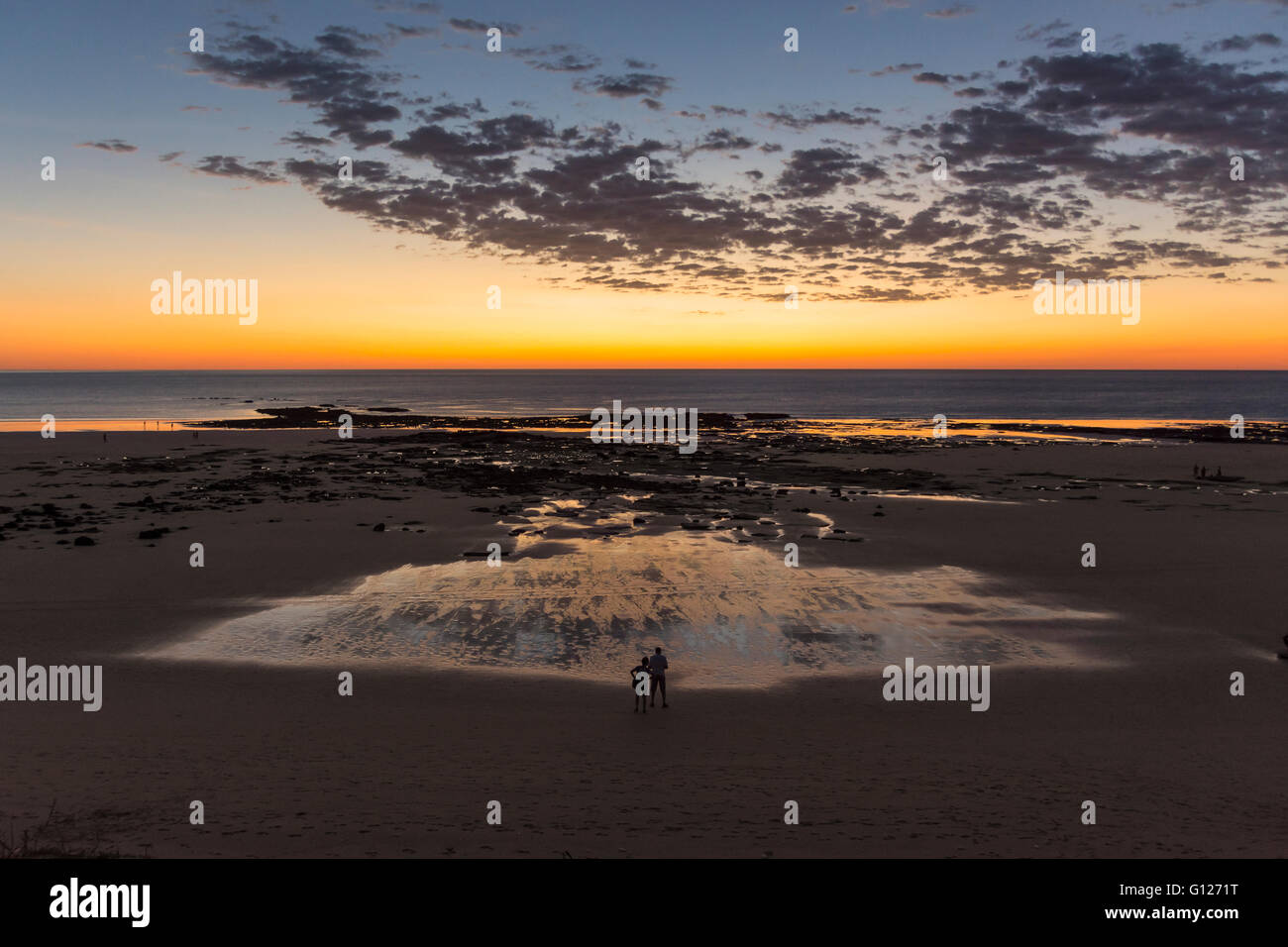 People watch the sunset over low tide at Cable Beach in Broome ...