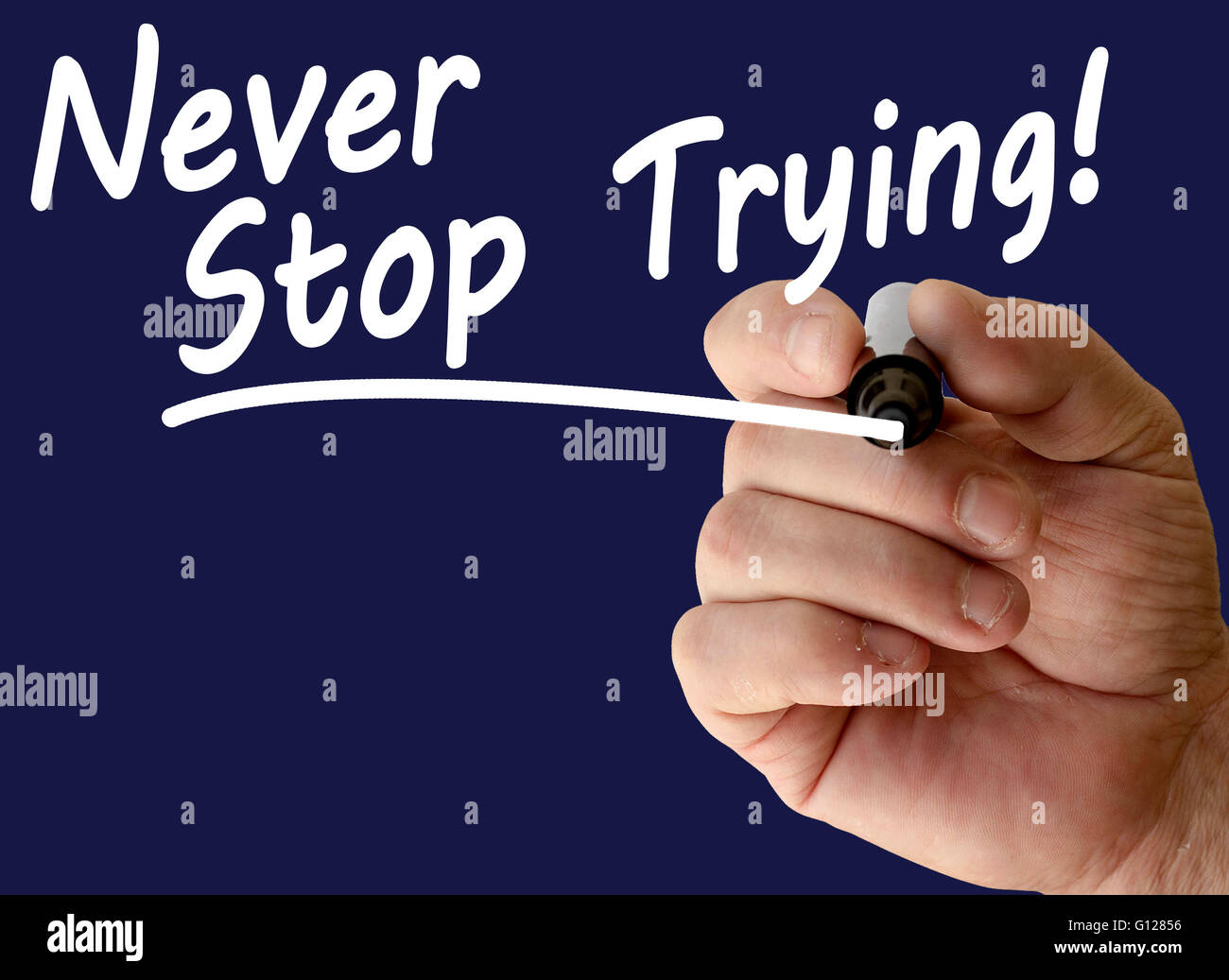 Hand writing never stop trying with white marker on blue wipe board ...