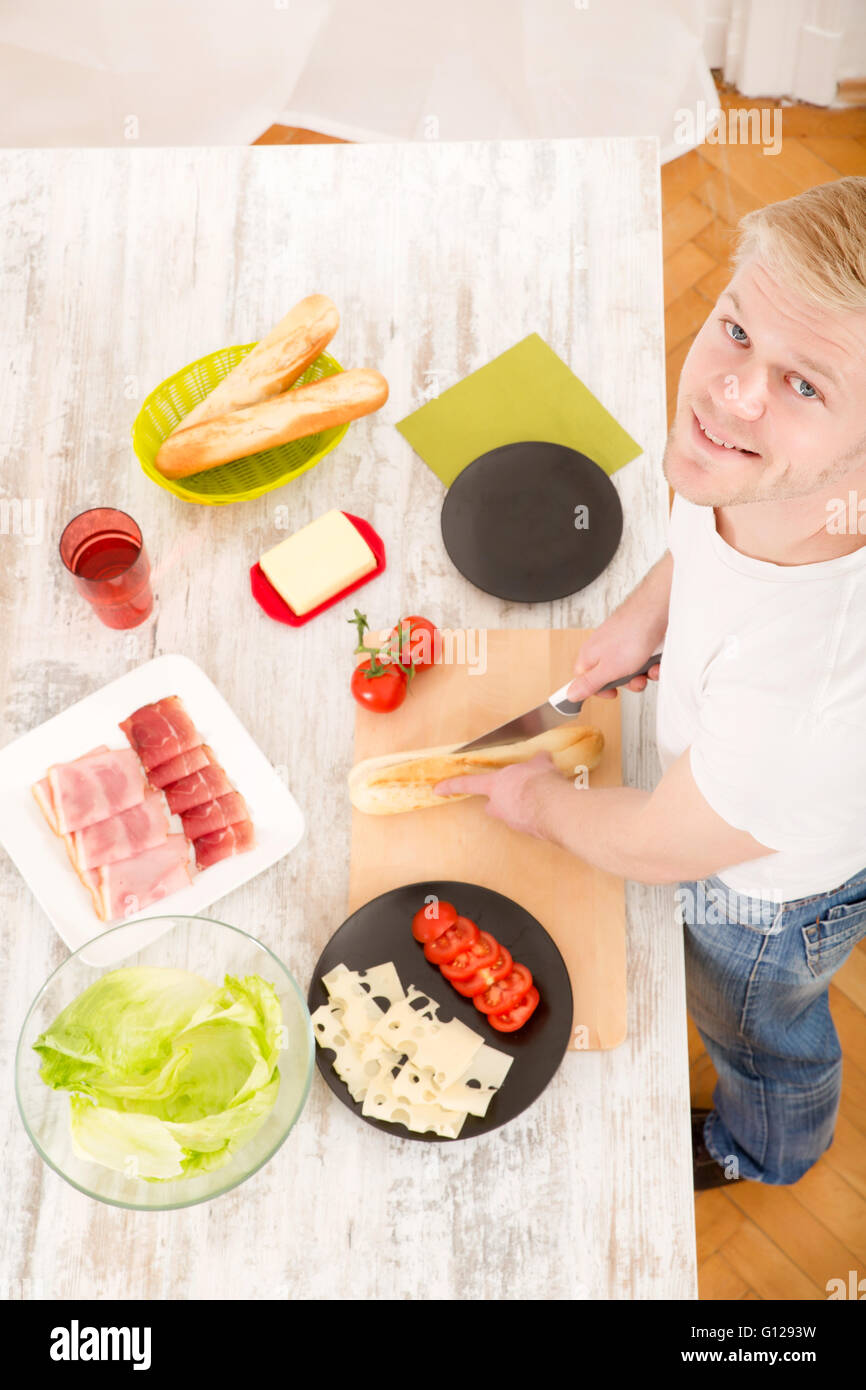 A young man preparing a sandwich in the kitchen Stock Photo - Alamy
