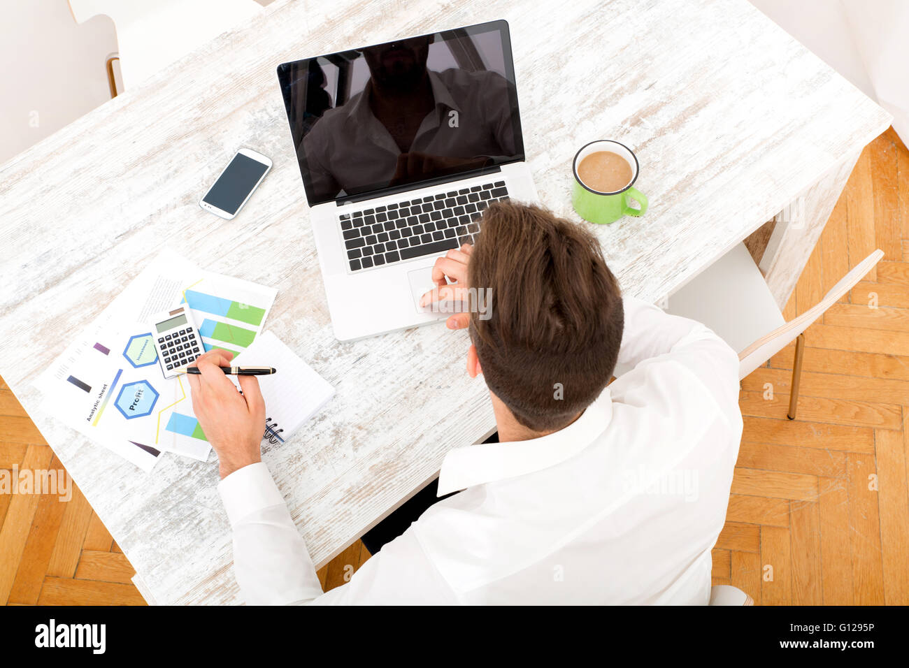 A young man sitting at the table with a laptop computer Stock Photo - Alamy