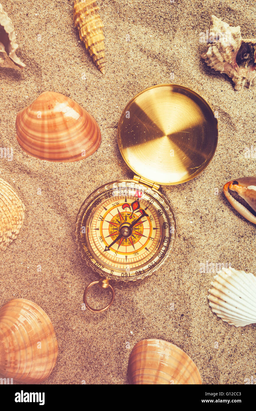 Top view of vintage compass and sea shells on sandy beach, navigational ...
