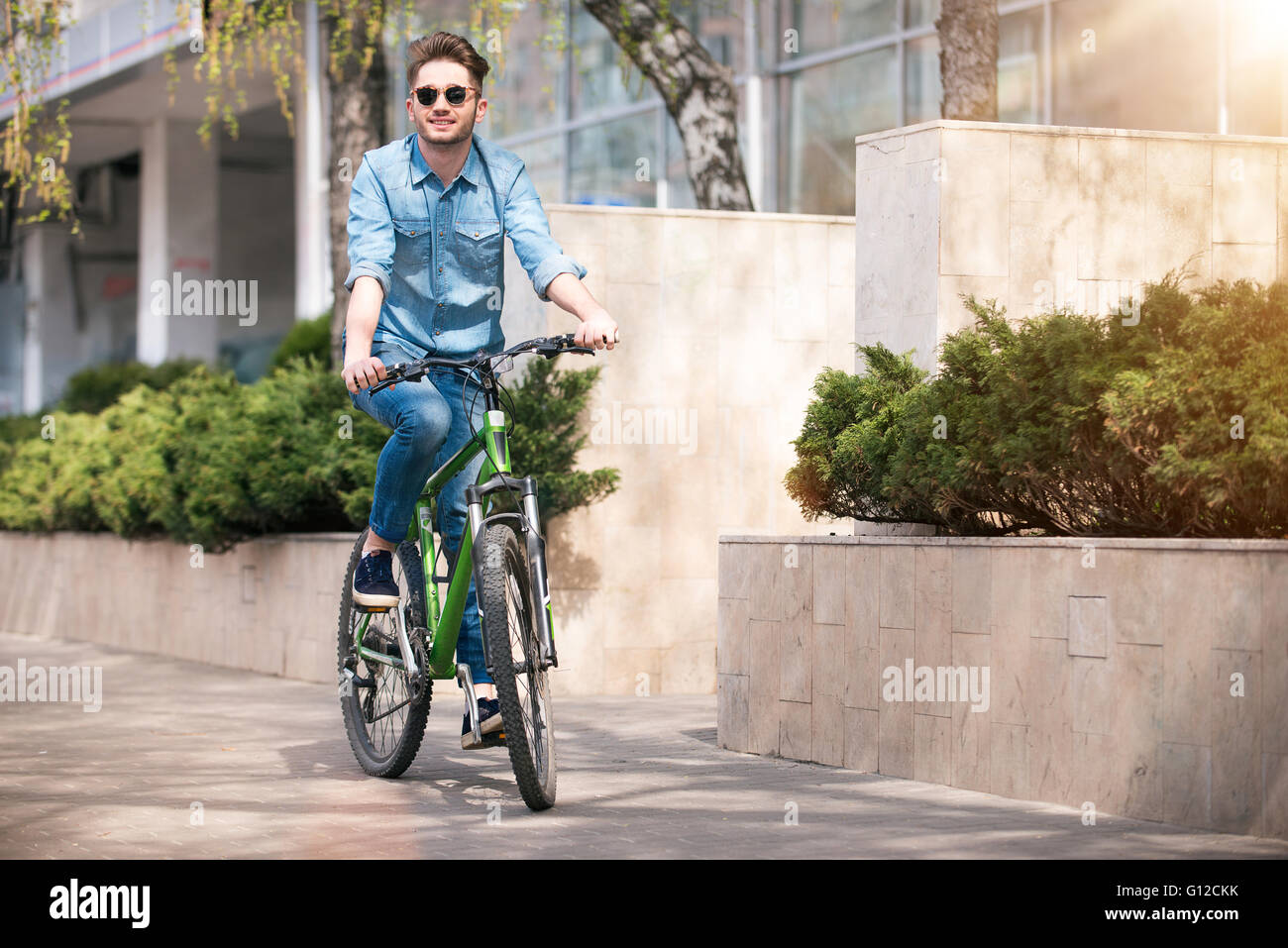 Cheerful guy riding a bike Stock Photo - Alamy