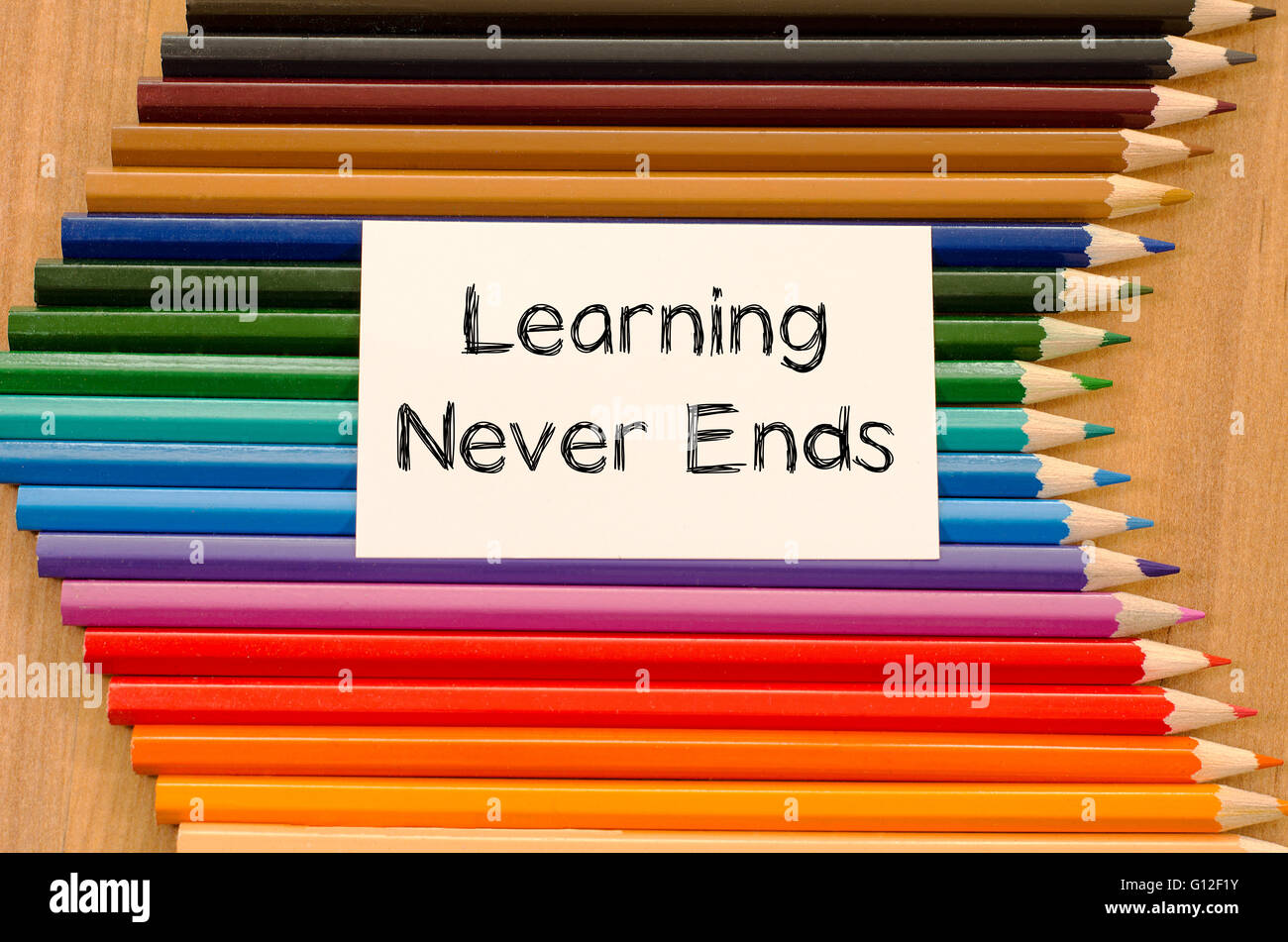 Learning never ends text concept and colored pencil on wooden ...