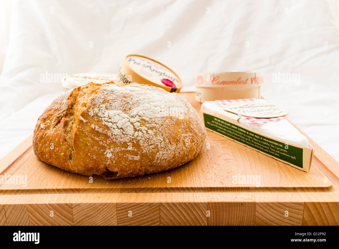 French Cheeses, boxed and packaged, on wooden chopping board with round ...